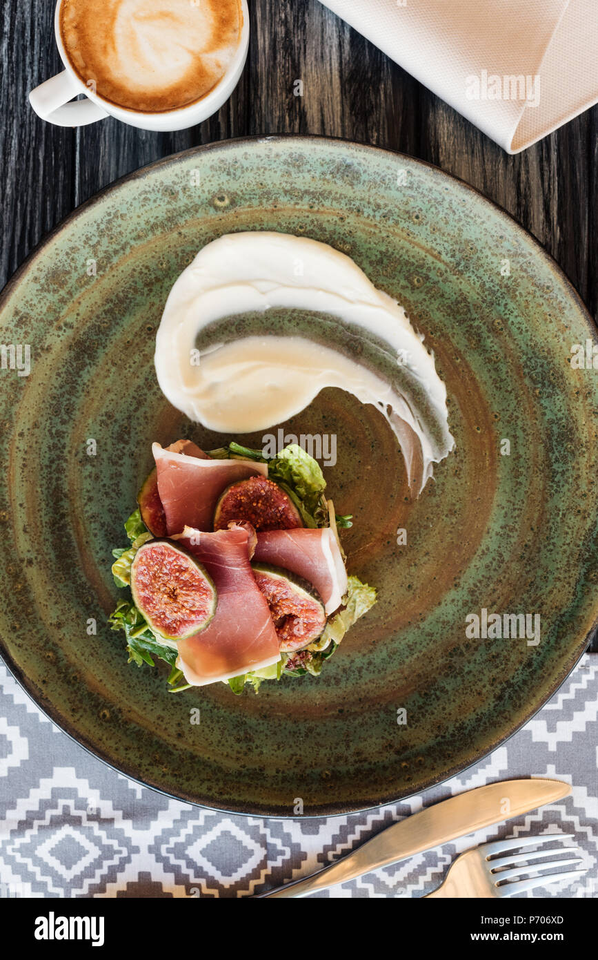 top view of delicious prosciutto on plate and cup of coffee on wooden ...