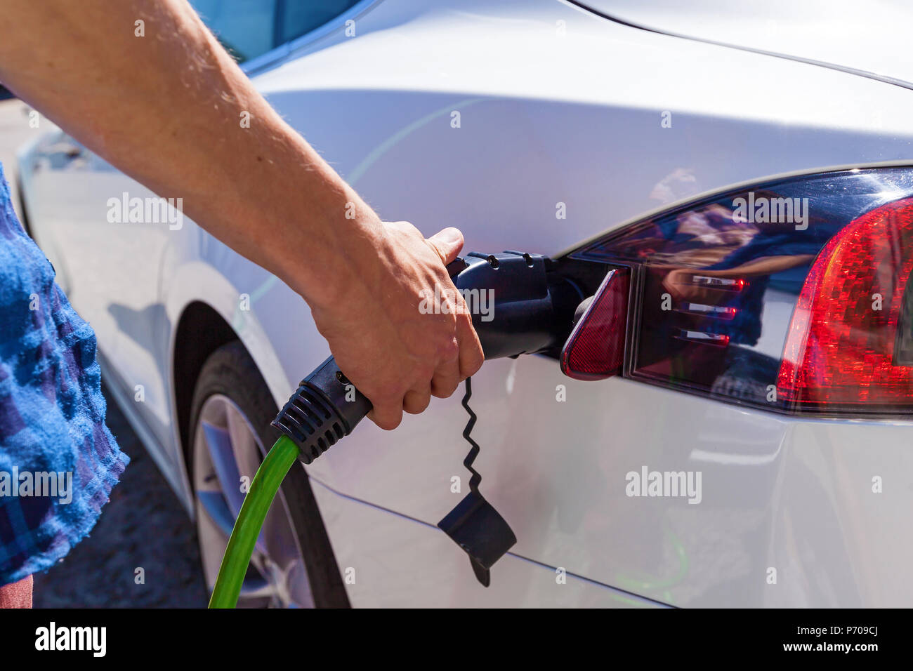 Man inserts the charger into an electric vehicle. Electric vehicle ...