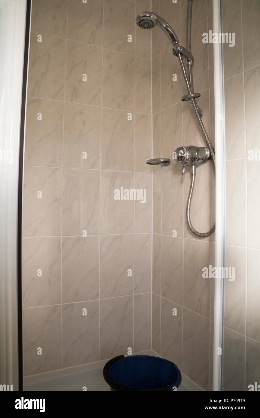 Collecting cold water in blue bucket from shower waiting for warm water ...