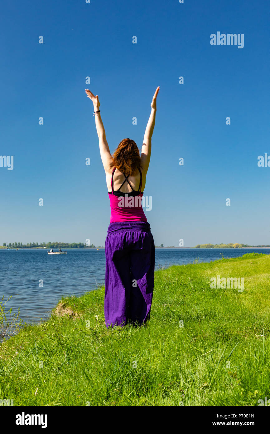 A yoga instructor demonstrates yoga poses during an outdoor yoga ...