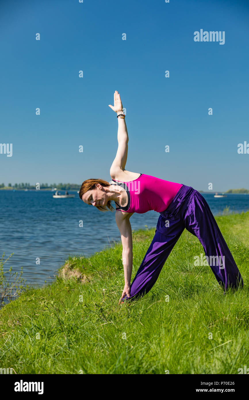 A yoga instructor demonstrates yoga poses during an outdoor yoga ...