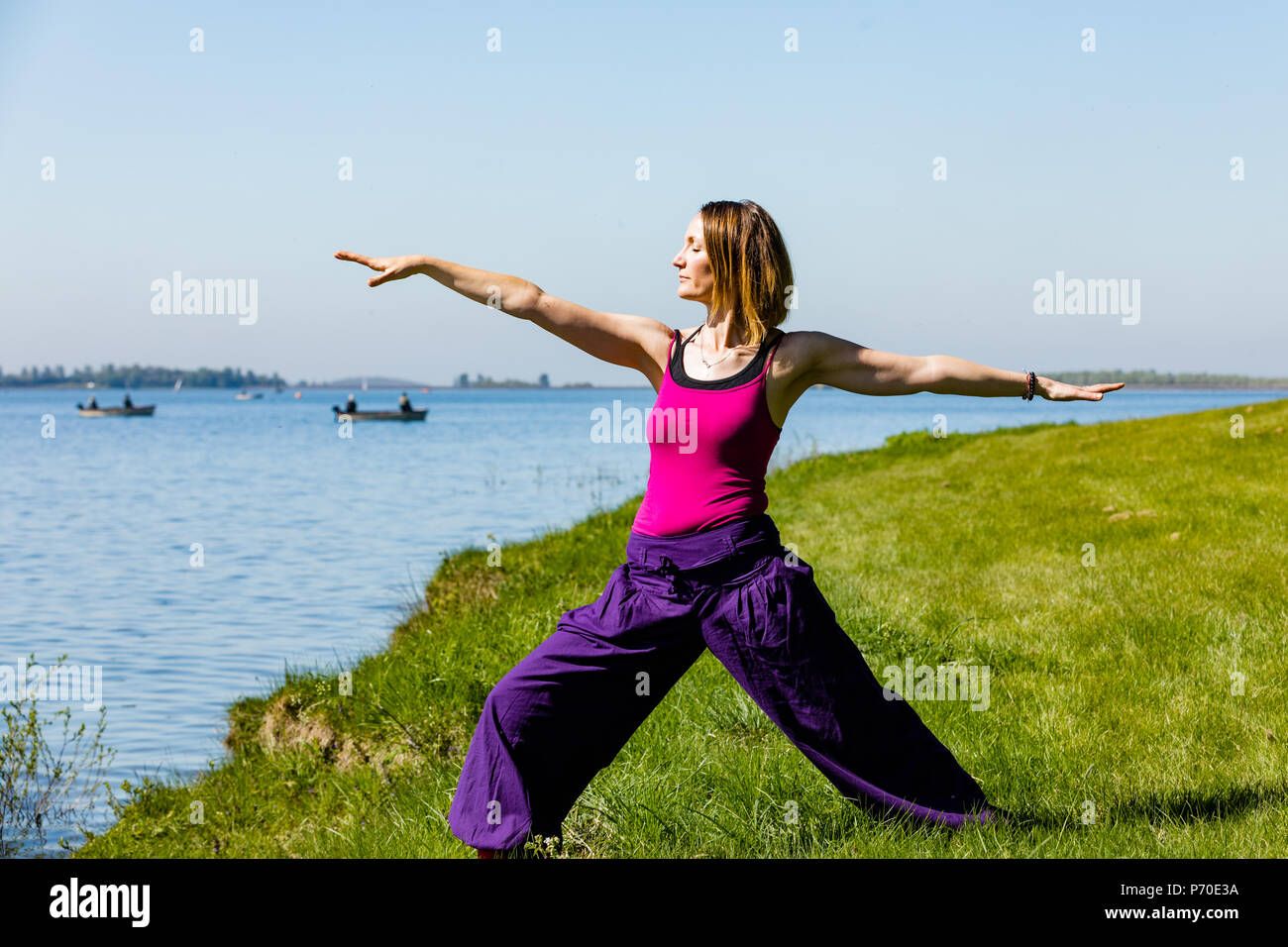A yoga instructor demonstrates yoga poses during an outdoor yoga ...