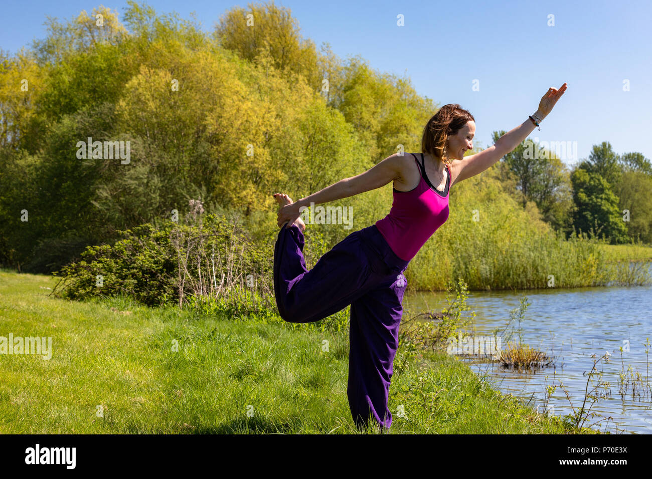 A yoga instructor demonstrates yoga poses during an outdoor yoga ...