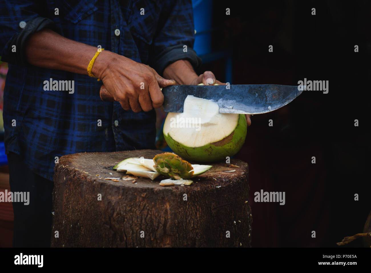 Man cuts young green coconut with a sharp chopper Stock Photo - Alamy