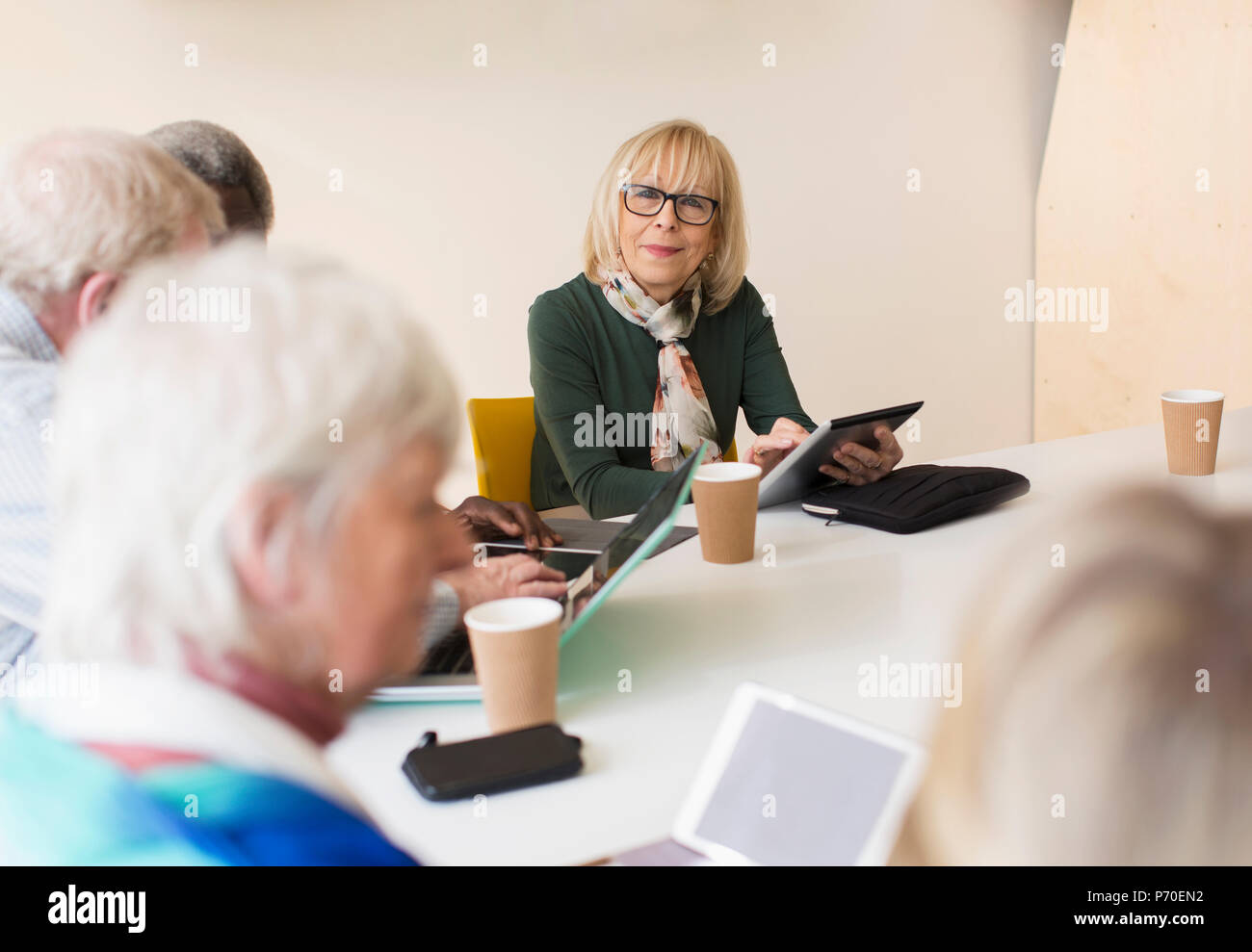 Portrait confident senior businesswoman with digital tablet leading ...