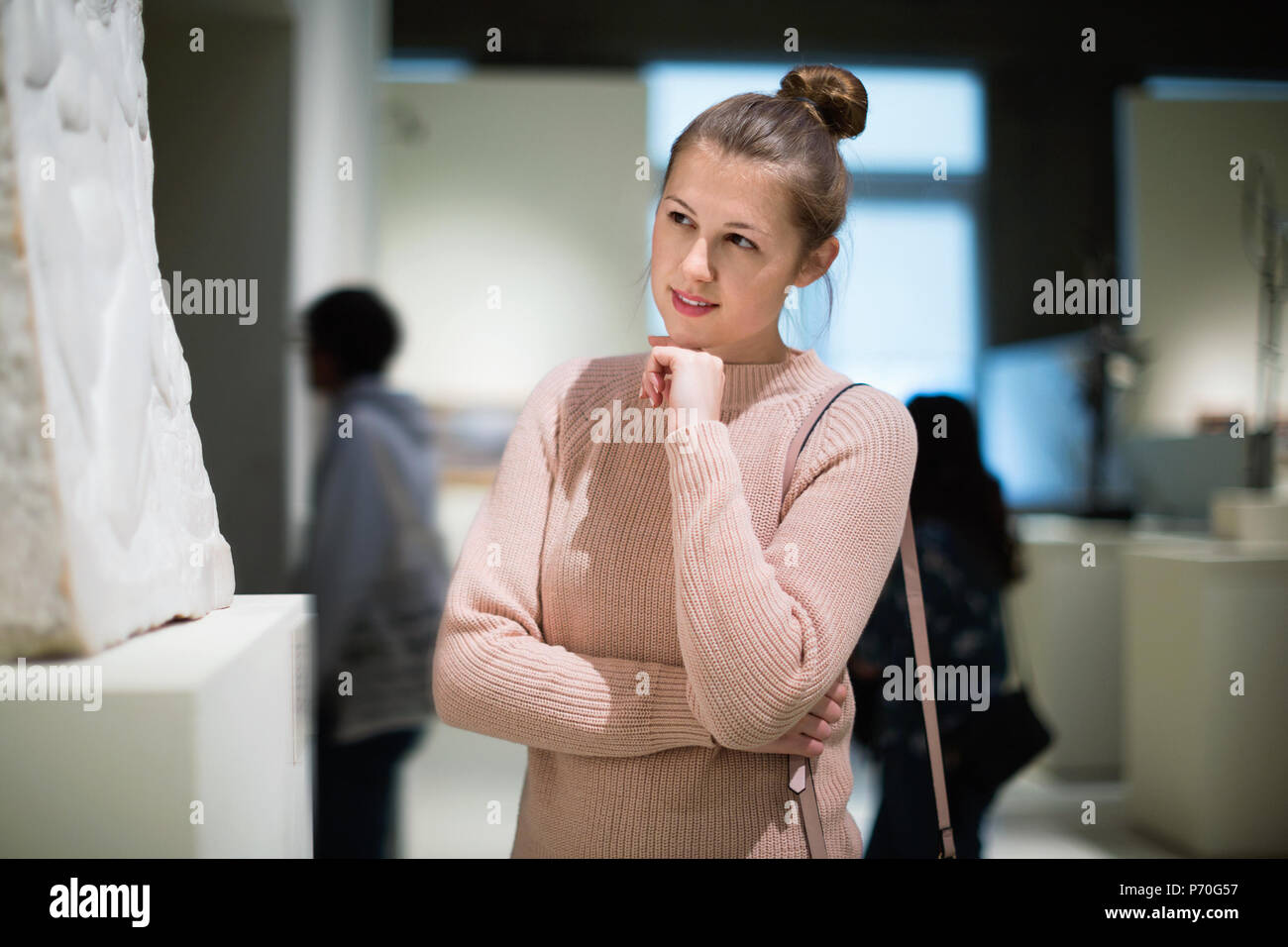 Happy cheerful female visitor looking at exhibition in museum of ...