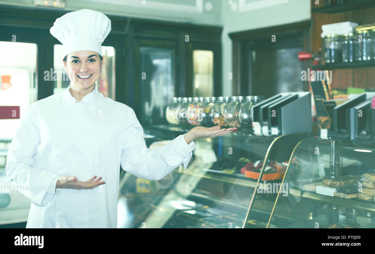 Young female assistant demonstrating assortment of confectionery Stock ...