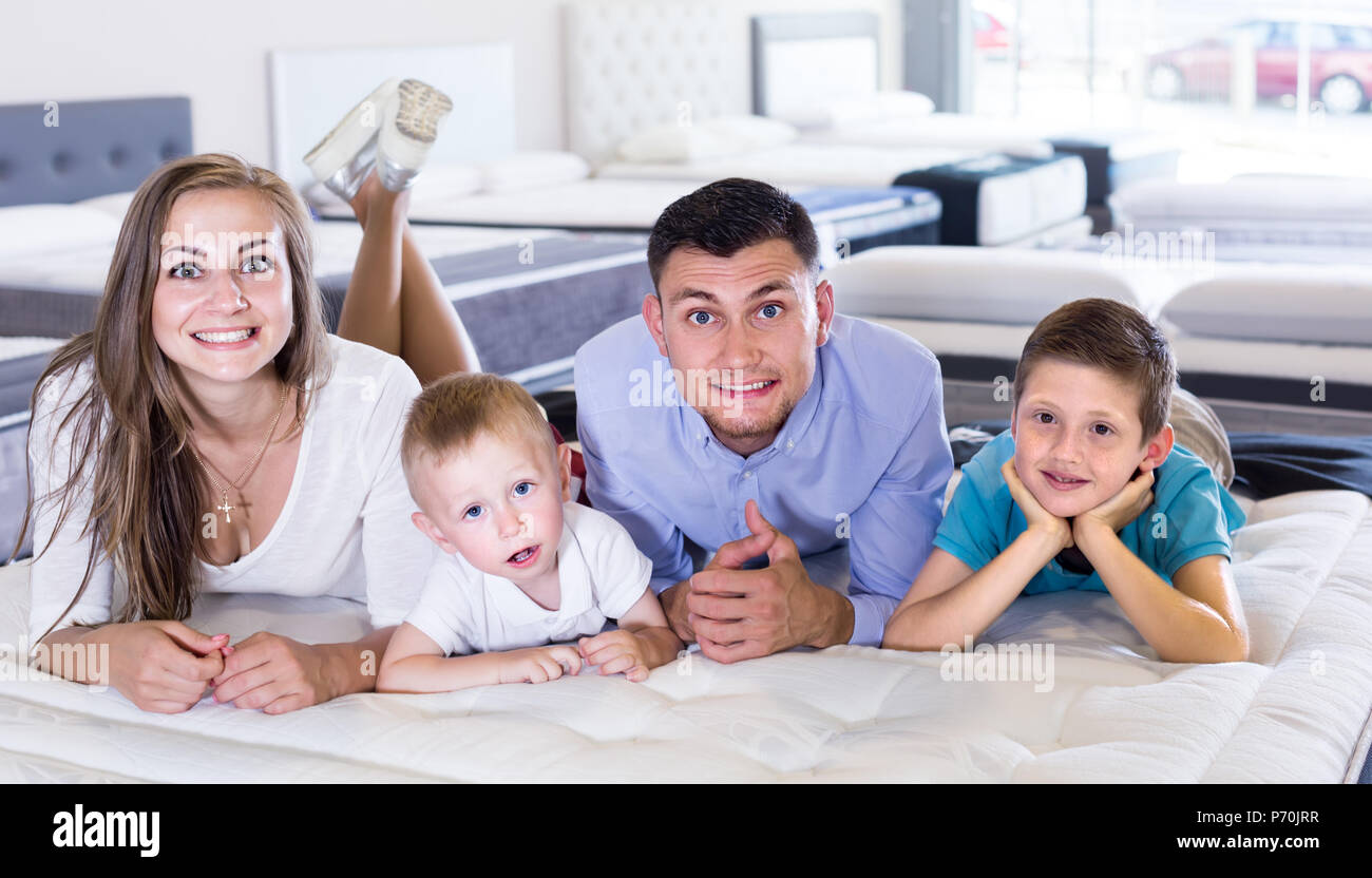 happy english parents with two young sons testing mattress in store ...