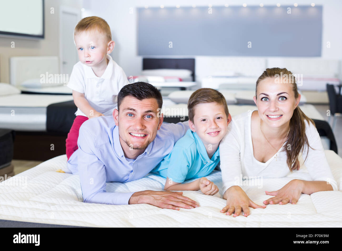 happy european parents with two young sons testing mattress in store ...