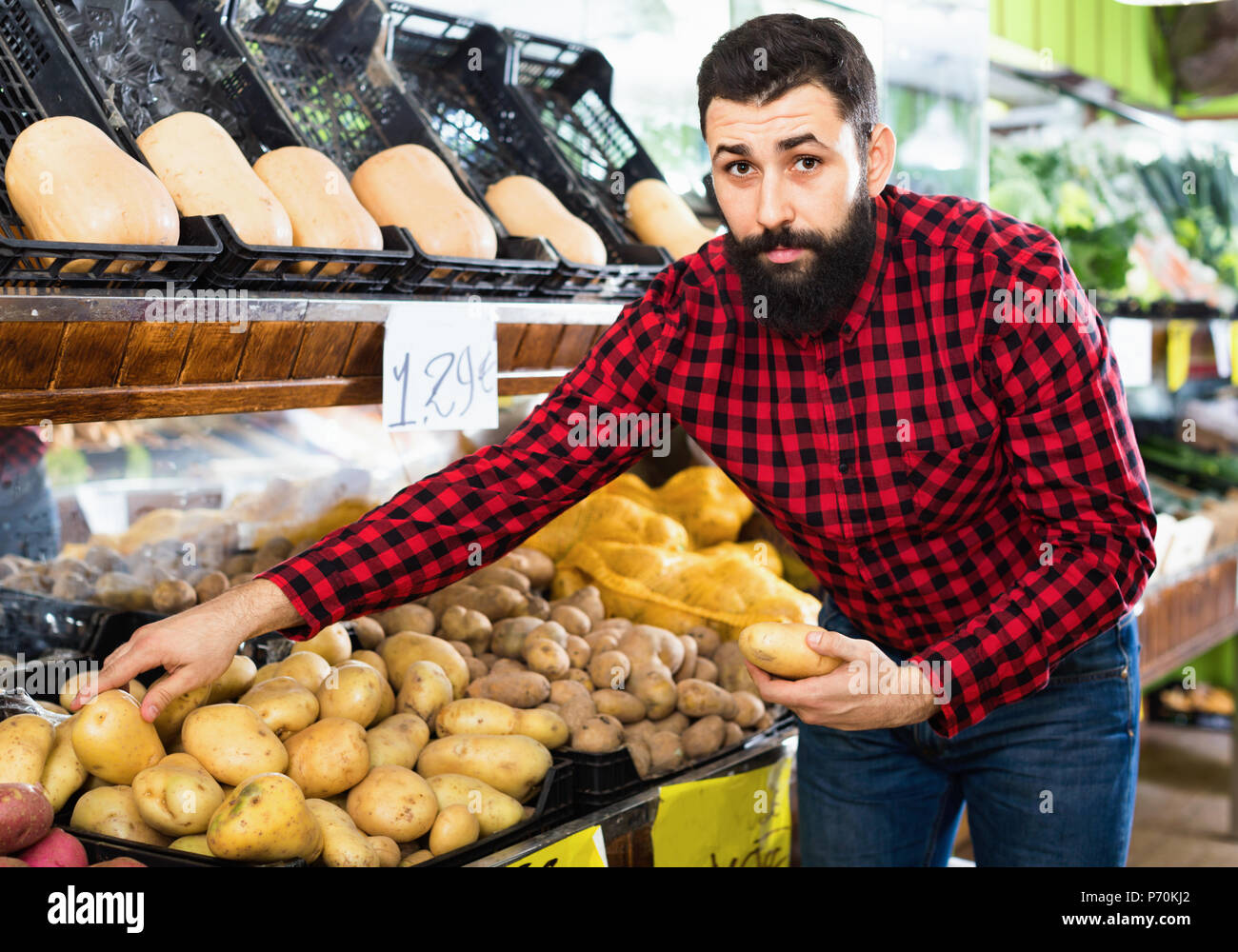 Cheerful positive male seller offering potatoes in grocery shop Stock ...