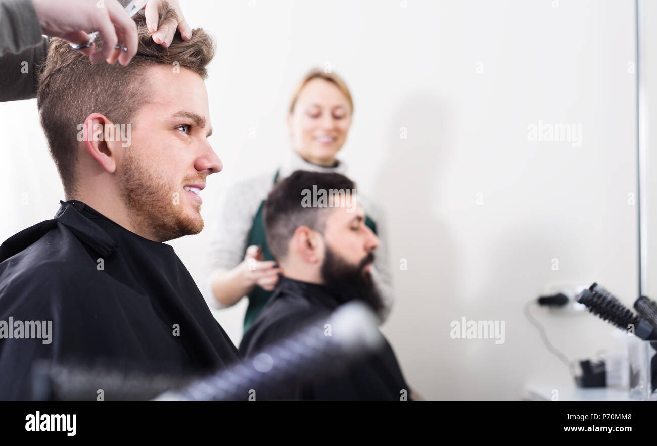 happy men clients waiting for their haircuts to be finished at hair ...