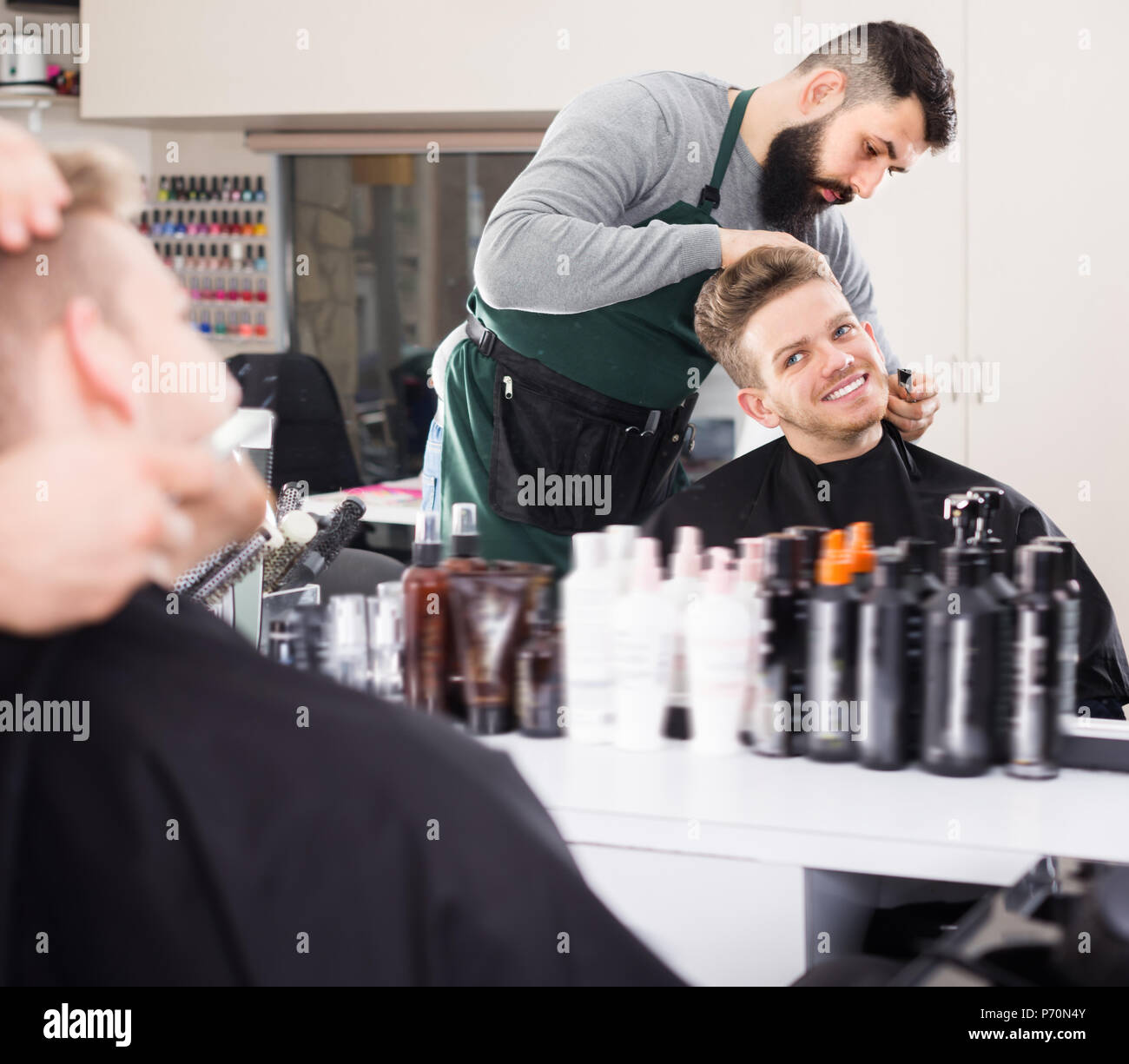 Glad guy stylist creating new shape for beard of client at hairdressing ...