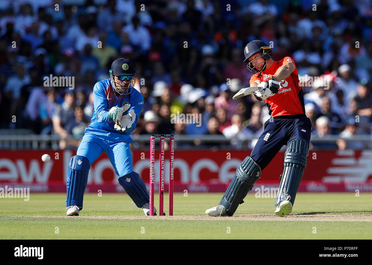 England's Jos Buttler hits a 4 watched by India wicket keeper MS Dhoni ...
