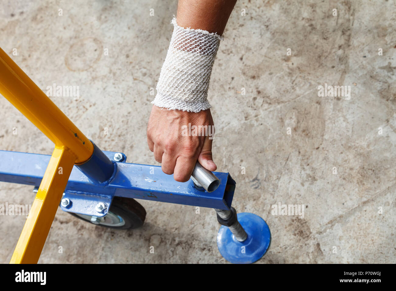 Worker with a bandaged patient hand twisting the locking screw on a ...
