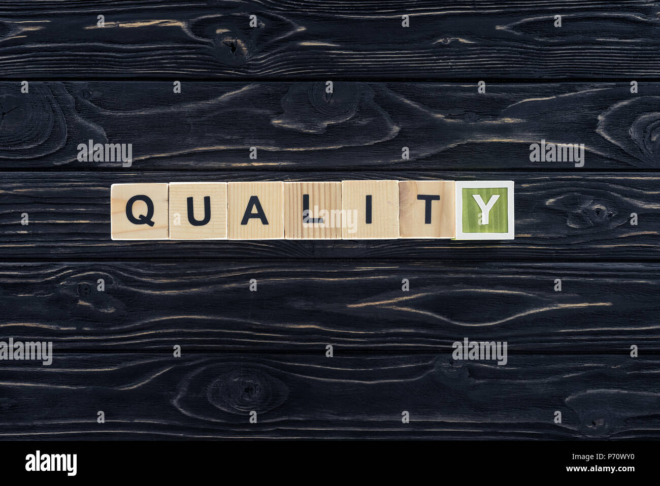 top view of word quality made of wooden blocks on dark wooden tabletop ...