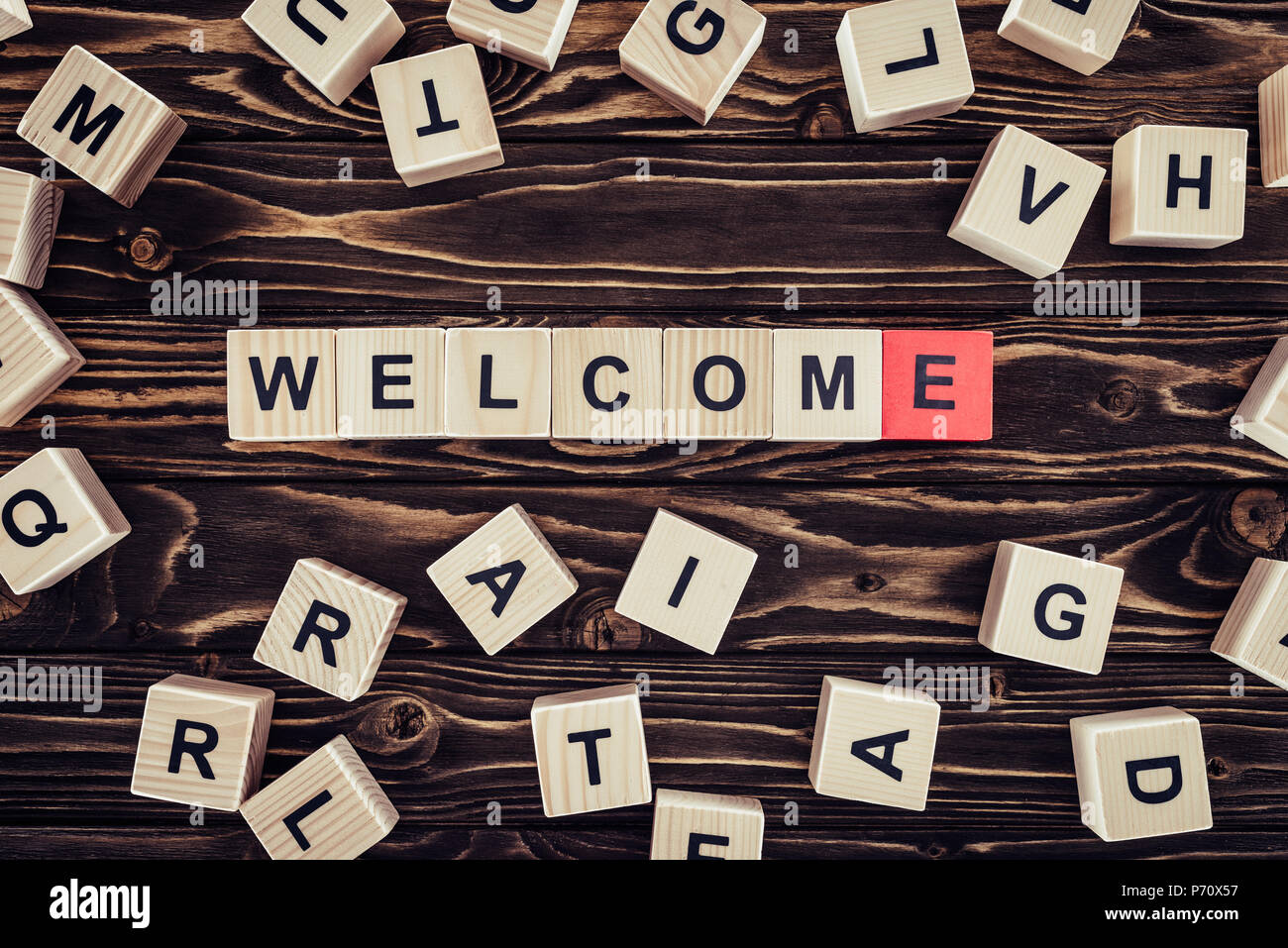 flat lay with wooden cubes arranged in welcome word on brown wooden ...