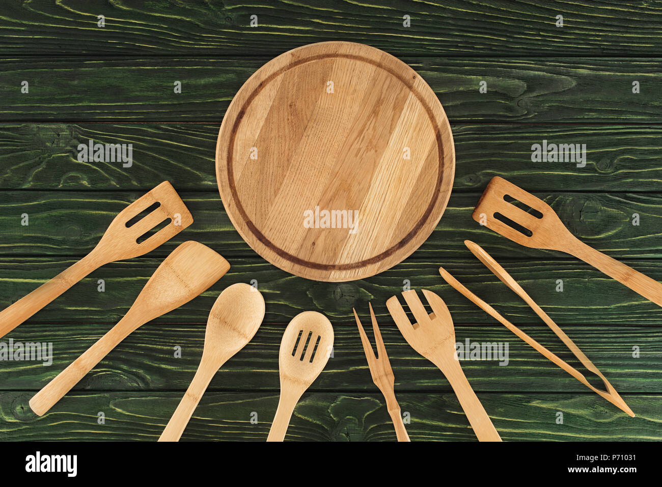 top view of round cutting board and wooden kitchen utensils on table ...