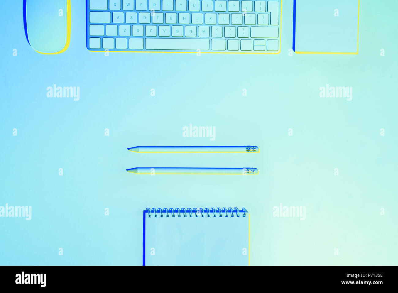 blue toned picture of computer keyboard and mouse, pencils and empty ...
