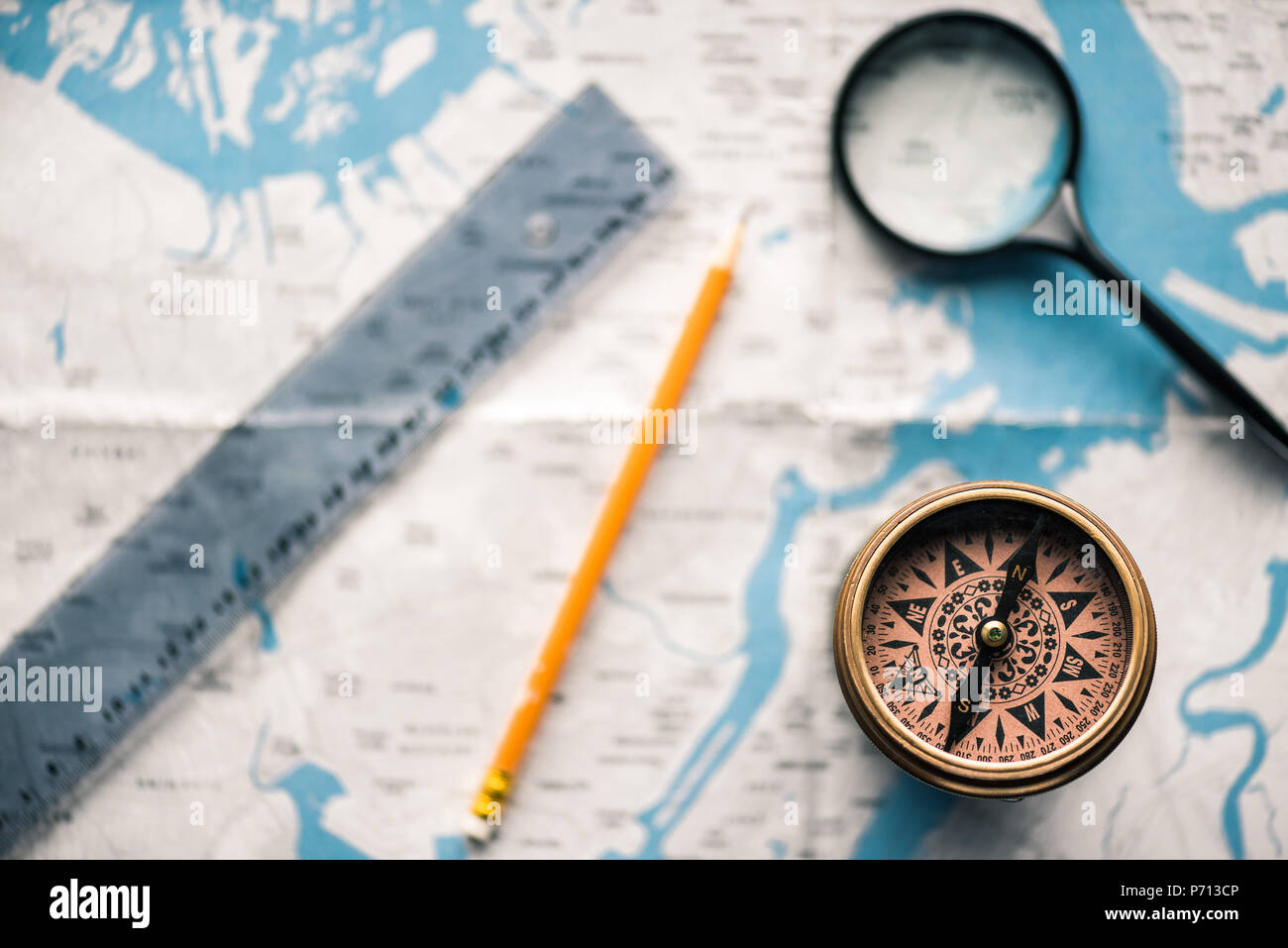 top view of vintage compass with ruler and magnifying glass on map ...