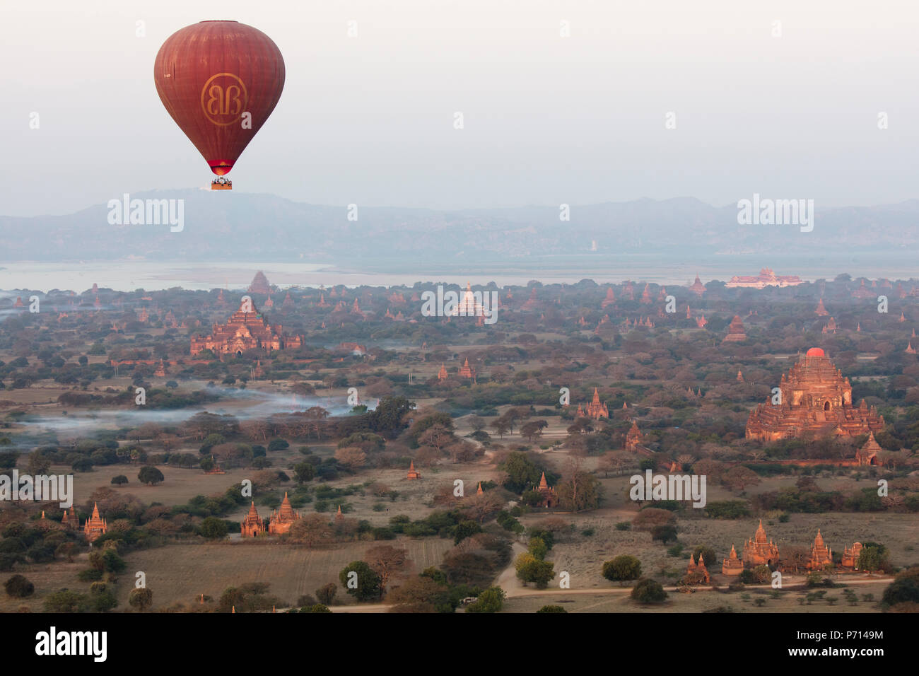 Hot air balloon flies over ancient Buddhist temples at dawn, Bagan ...