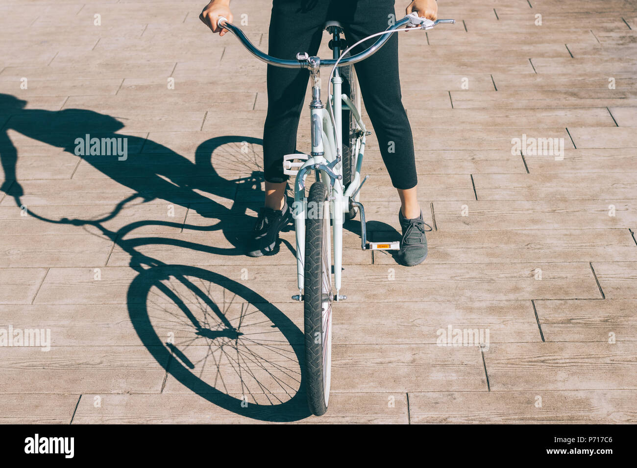 Slender young woman resting on a vintage bicycle on the embankment ...