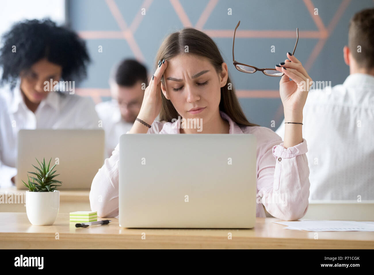 Tired female employee suffering from headache at workplace Stock Photo ...