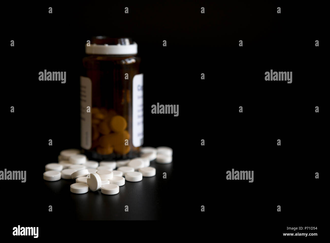 Tablets on a black background from a jar. jar with pills on a black ...