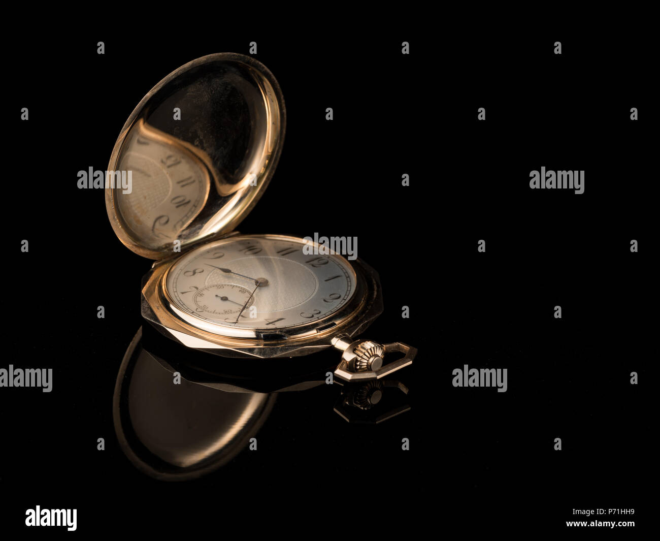 Closeup of an old, used golden pocket watch with open lid on a black ...