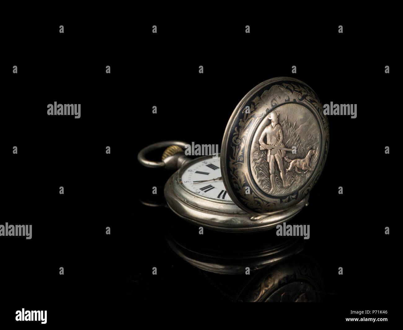 Closeup of an old pocket watch on a black reflective surface, open lid ...