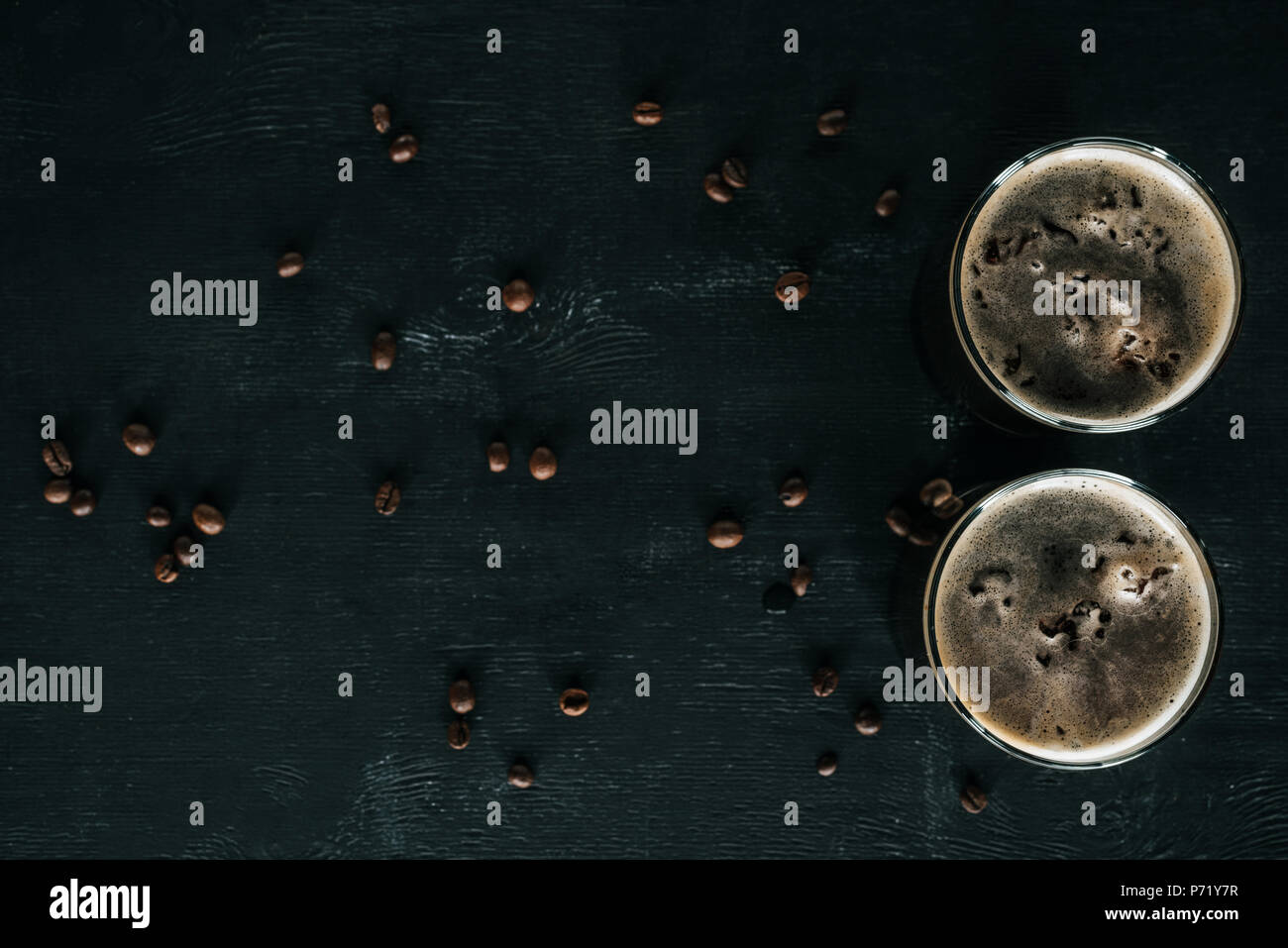 top view of glasses of cold brewed coffee with ice on dark surface with ...