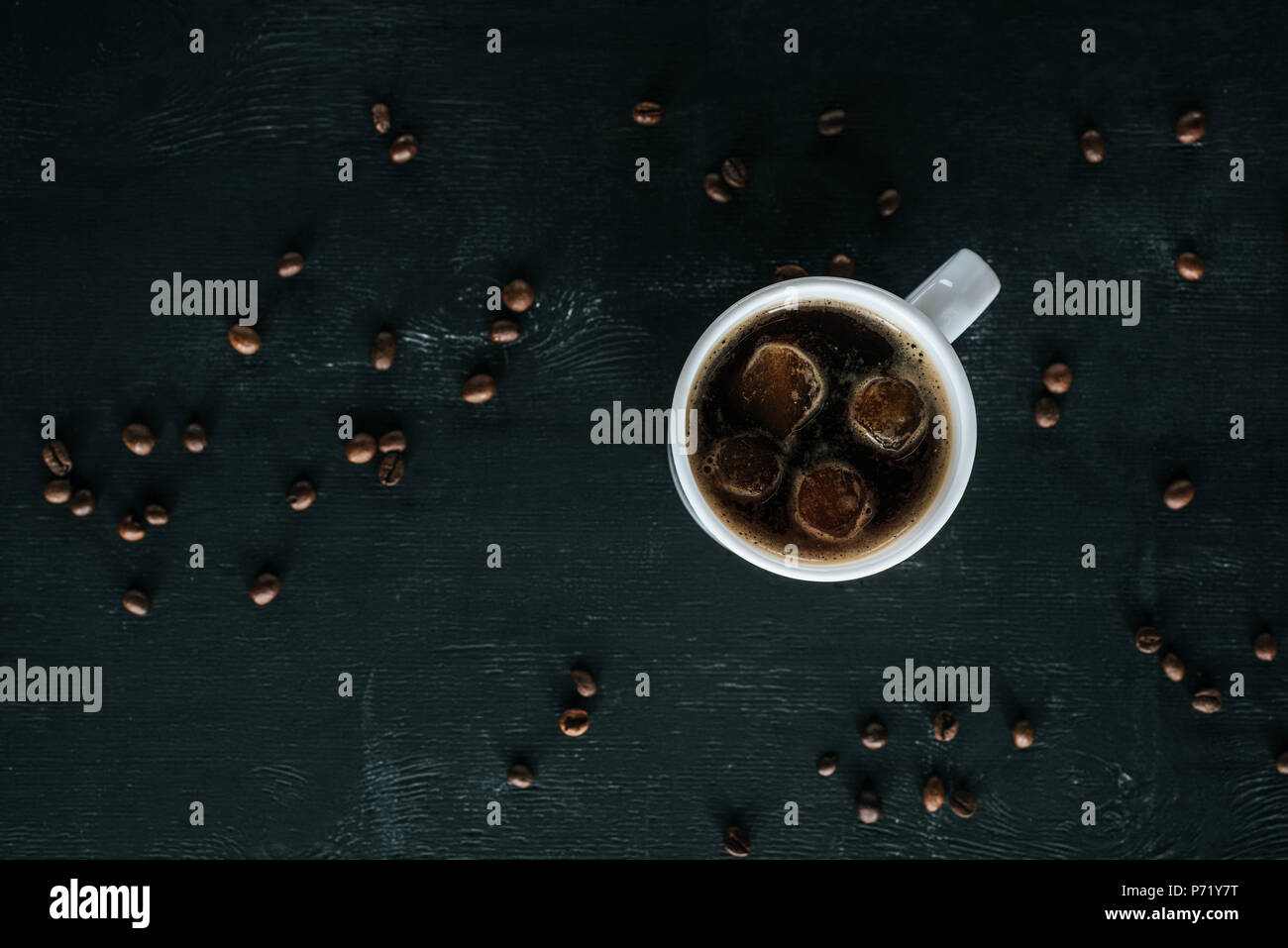 top view of mug of cold iced coffee on dark tabletop with roasted ...