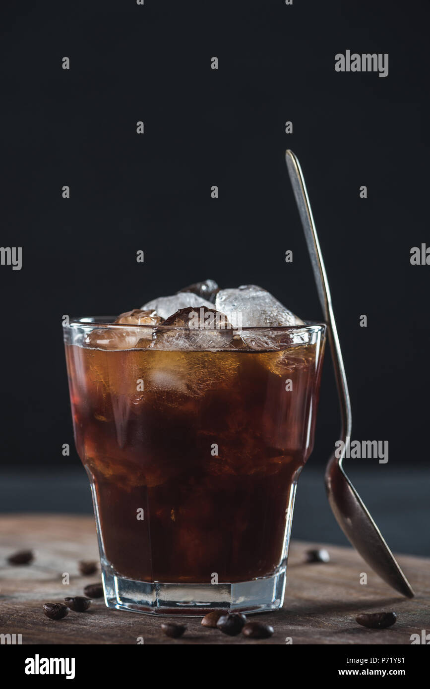 close up view of glass of cold brewed coffee with spoon on wooden ...