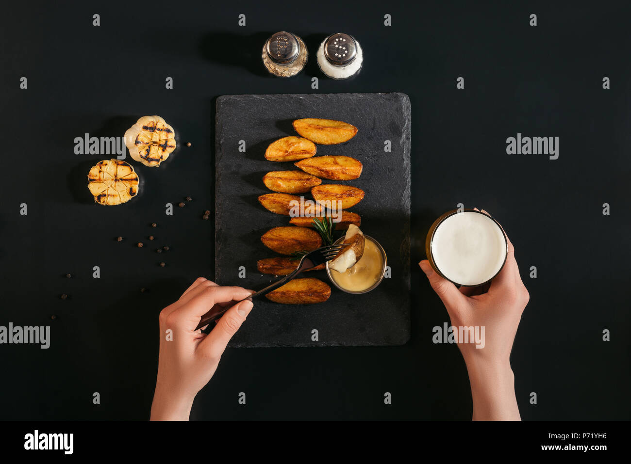 cropped shot of person drinking beer and eating baked potatoes with ...