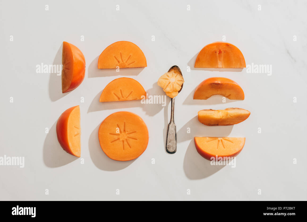 elevated view of persimmons pieces and spoon on white Stock Photo - Alamy
