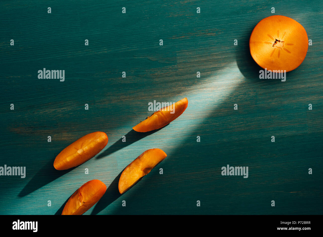 top view of persimmons on turquoise table with light Stock Photo - Alamy