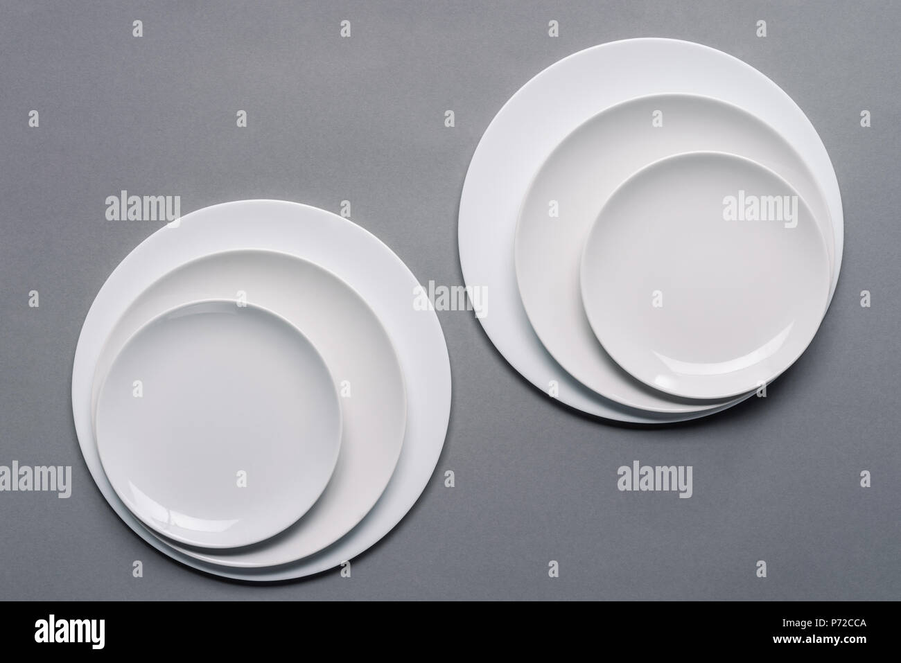 Shiny white kitchen ceramic plates on grey background Stock Photo - Alamy