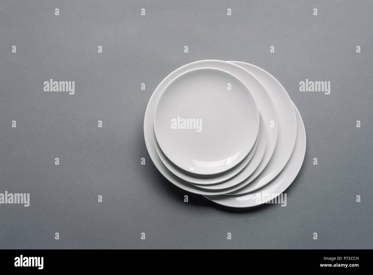 Stack of white porcelain plates on grey background Stock Photo - Alamy