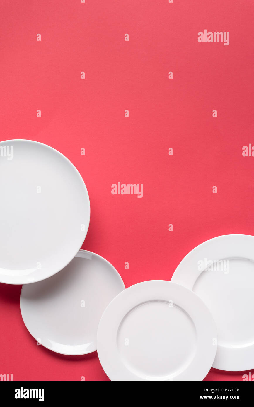 Composition of white plates on red background Stock Photo - Alamy
