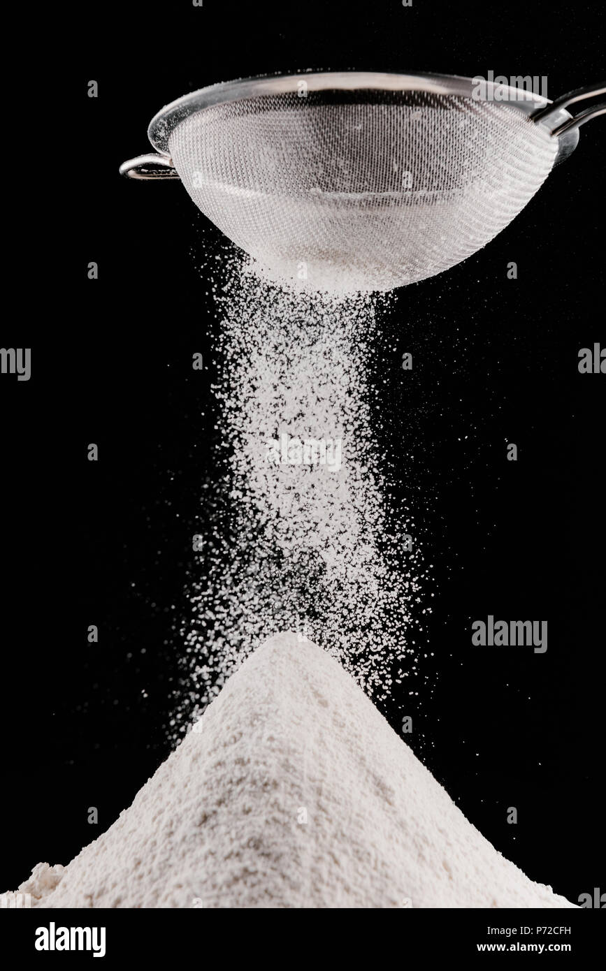 flour falling from sieve on pile isolated on black Stock Photo - Alamy