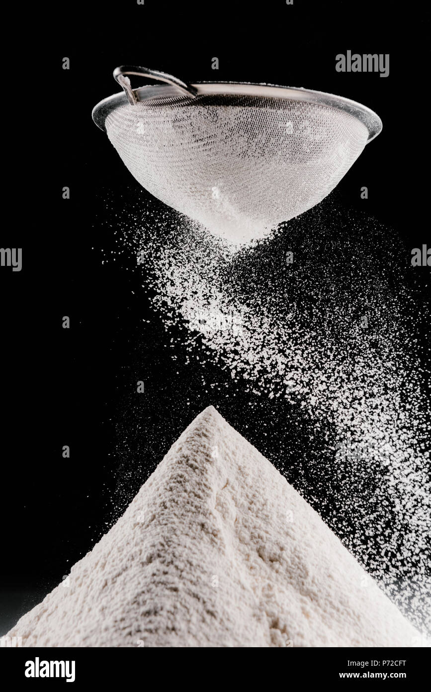 flour falling from sieve on pile isolated on black Stock Photo - Alamy