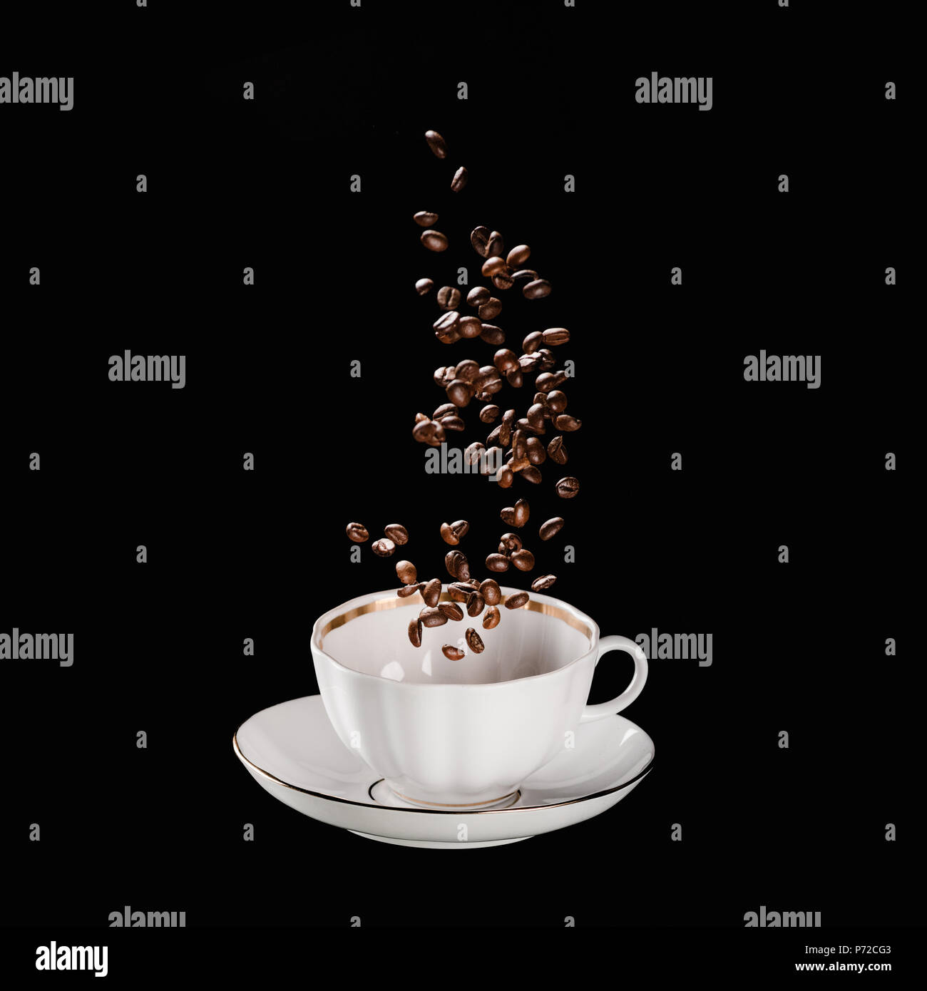 coffee beans falling into cup isolated on black Stock Photo - Alamy