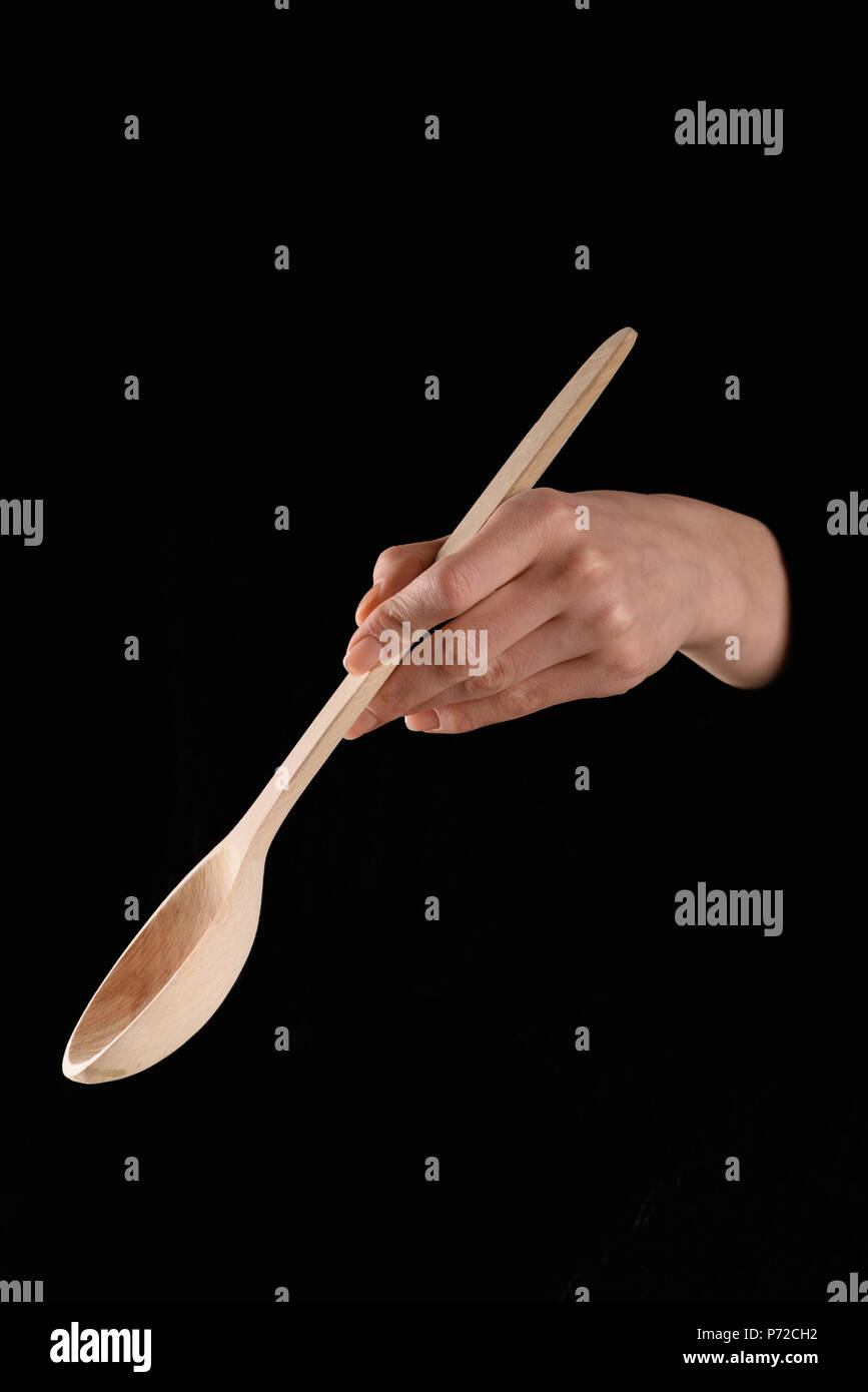 cropped image of woman holding wooden spatula isolated on black Stock ...