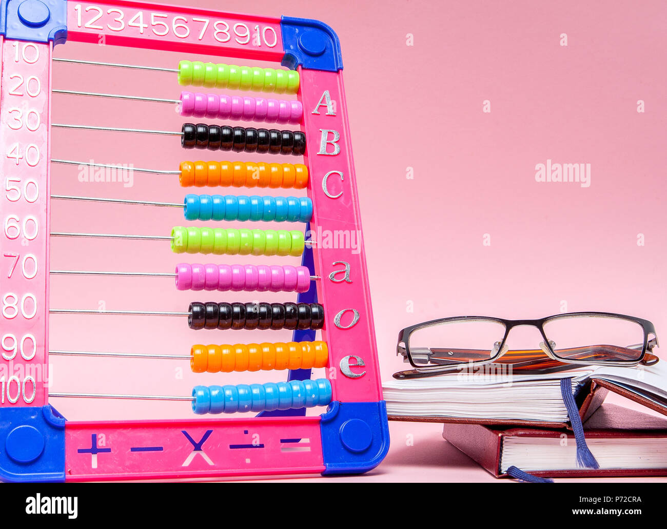Colored Abacus, Glasses and Notebook on pink background. Education ...