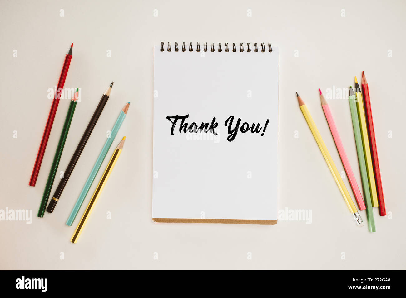 top view of notepad with thank you lettering and colorful pencils ...