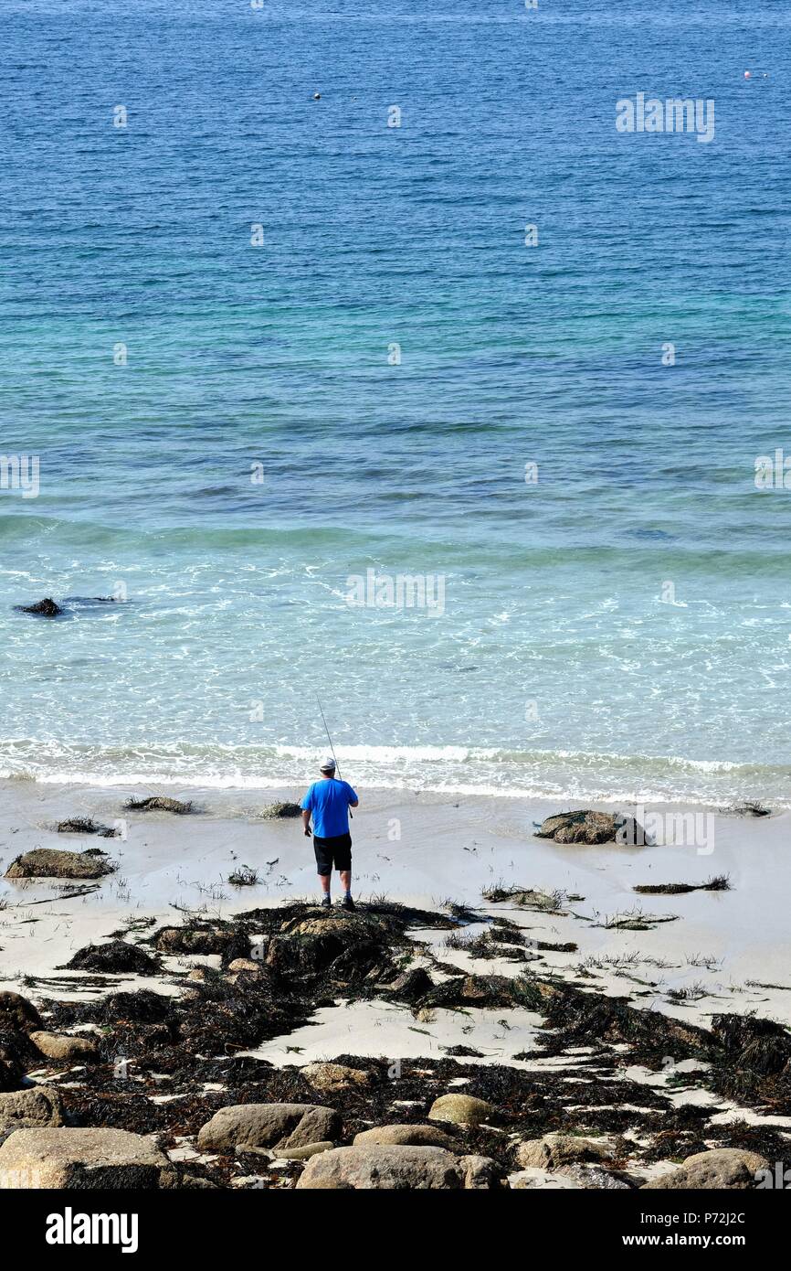 Single male fisherman beach fishing off the beach at Sennen Cove on a ...