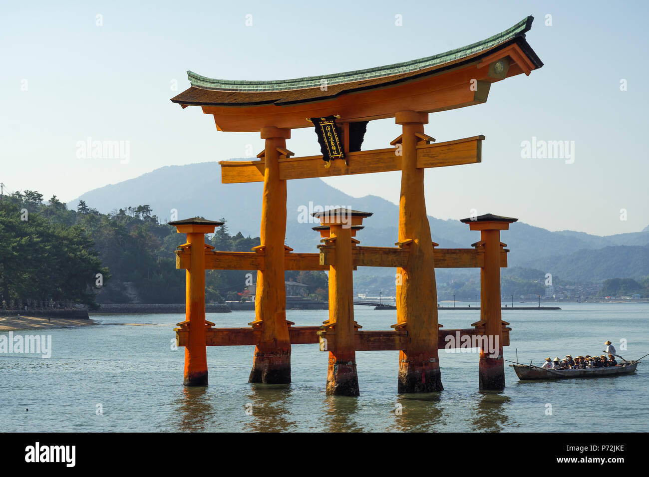 Tourist passing through the floating red wooden torii gate of Miyajima ...