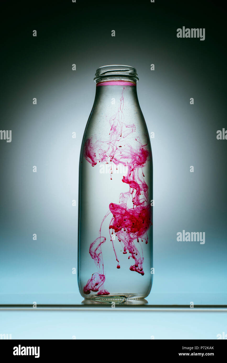 close up view of pink paint splash in bottle of water Stock Photo - Alamy