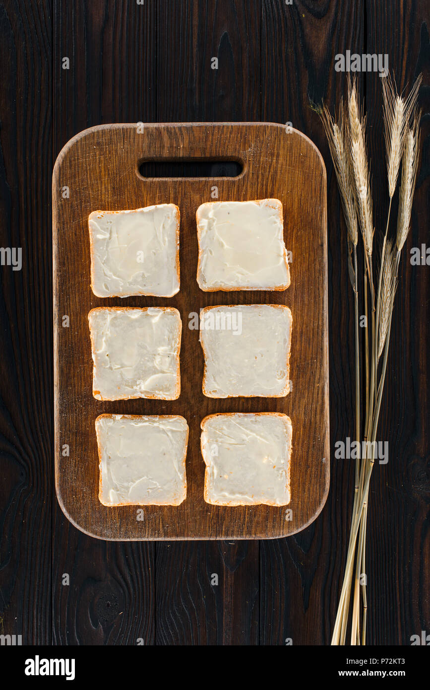 top view of fresh toasts with butter and spikelets on wooden table ...