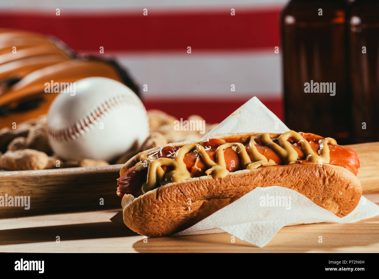close-up view of hot dog, baseball bat and sport equipment on wooden ...