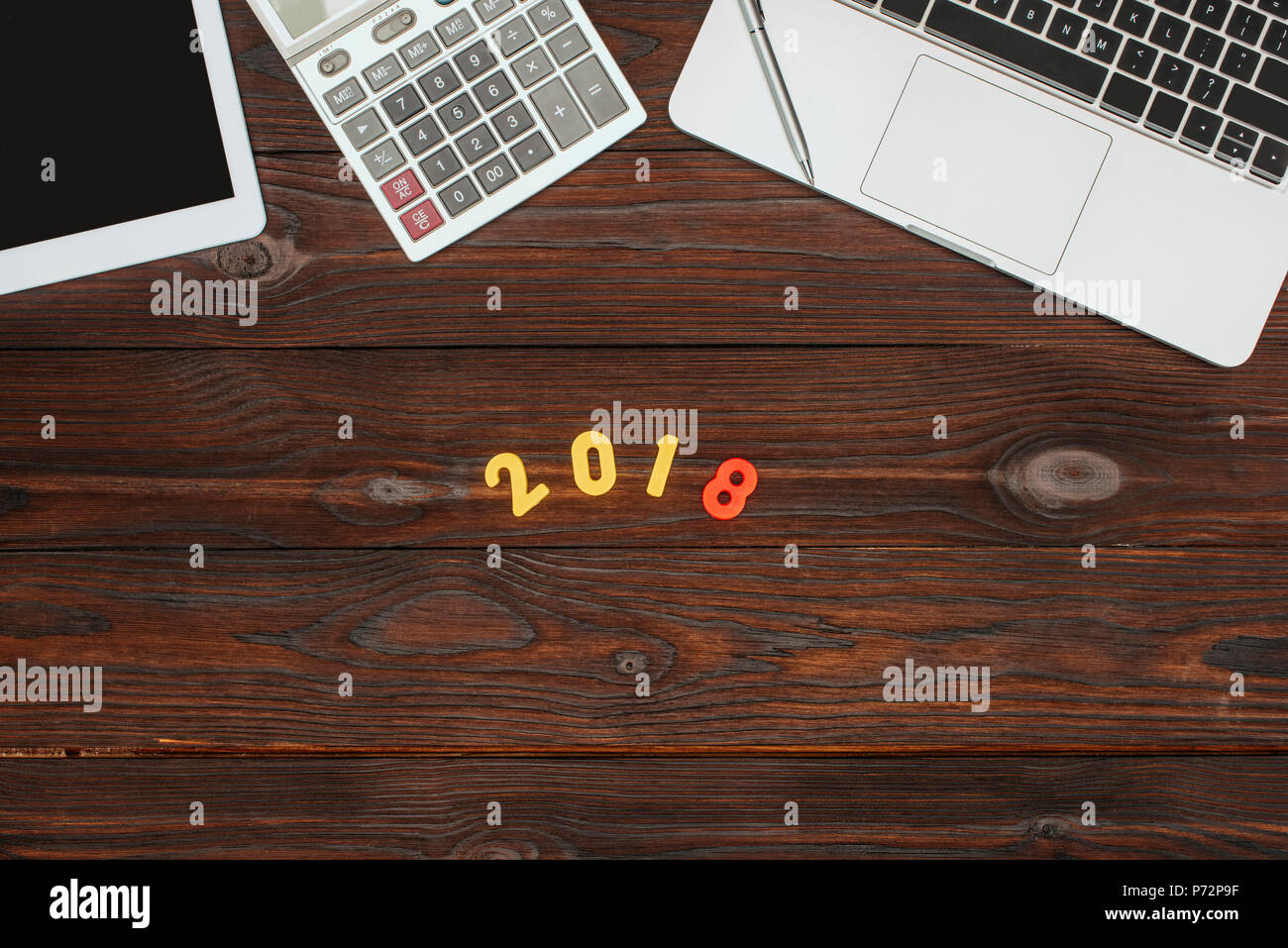 top view of laptop, tablet, calculator and 2018 numbers on wooden ...